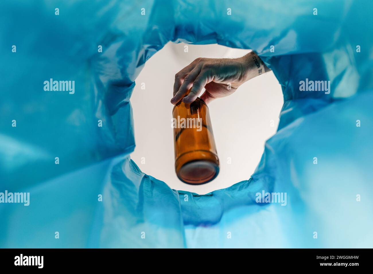 Man throwing glass bottle into recycling bin. Empty alcohol bottle ...