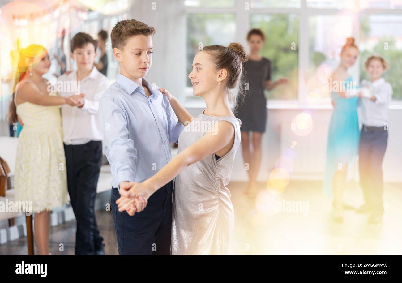 Positive teen boy and girl are dancing classic version of waltz in ...