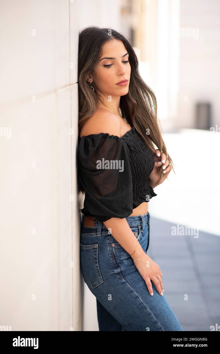 Beautiful woman leaning against wall outdoors looking down Stock Photo ...