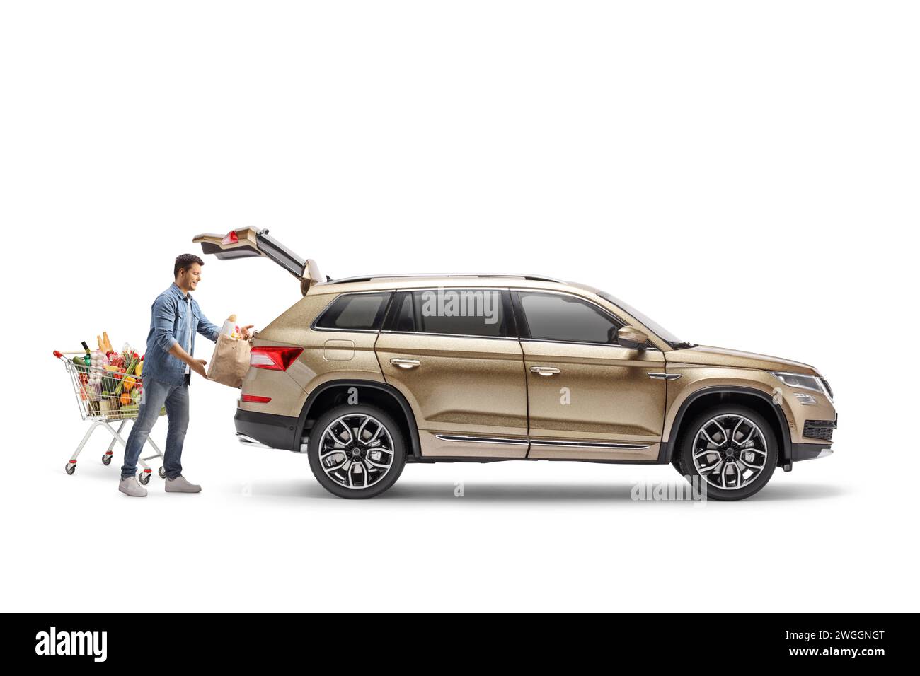 Young man with a shopping cart loading groceries in the trunk of a SUV ...