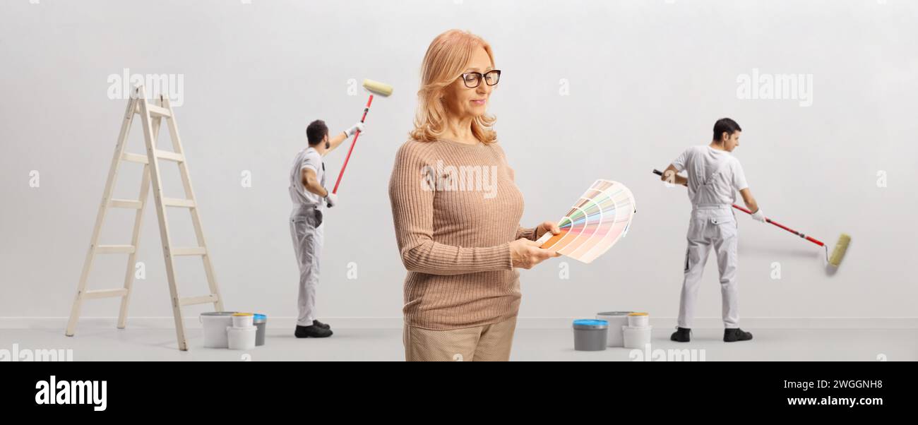 Woman chosing a paint color and workers painting a wall Stock Photo - Alamy