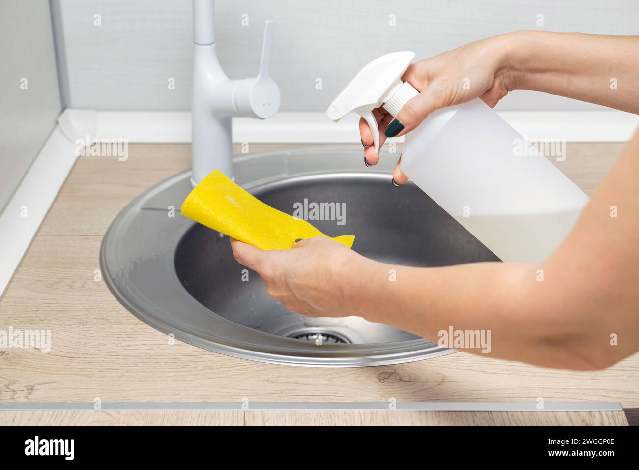 woman washing the sink in the kitchen, close up. hand wipes a stainless ...