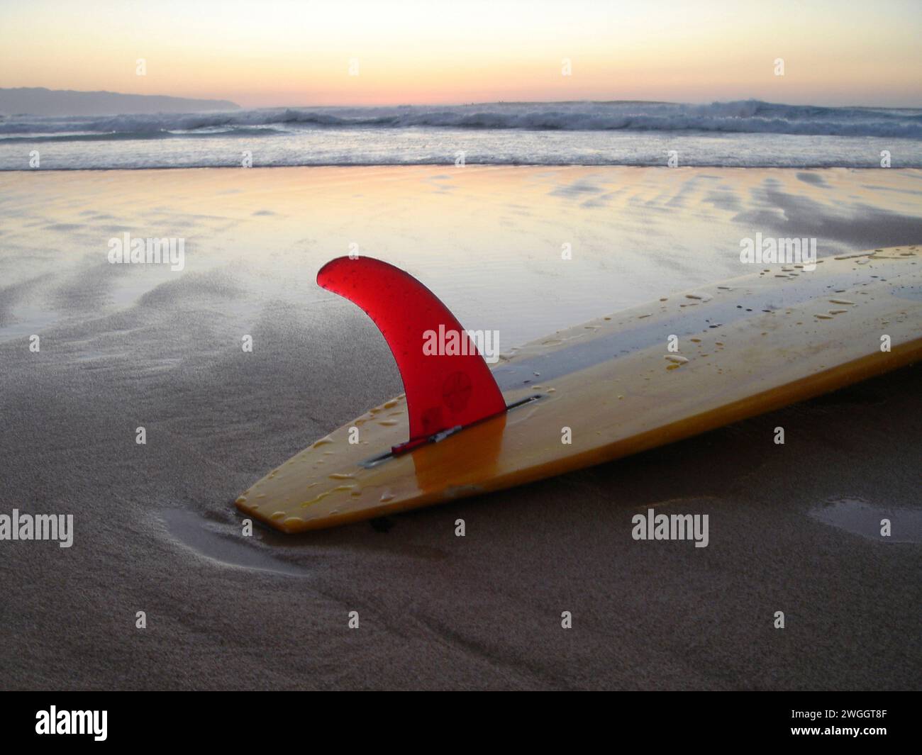surfboard with red single fin washed up at Pipeline, against the ...