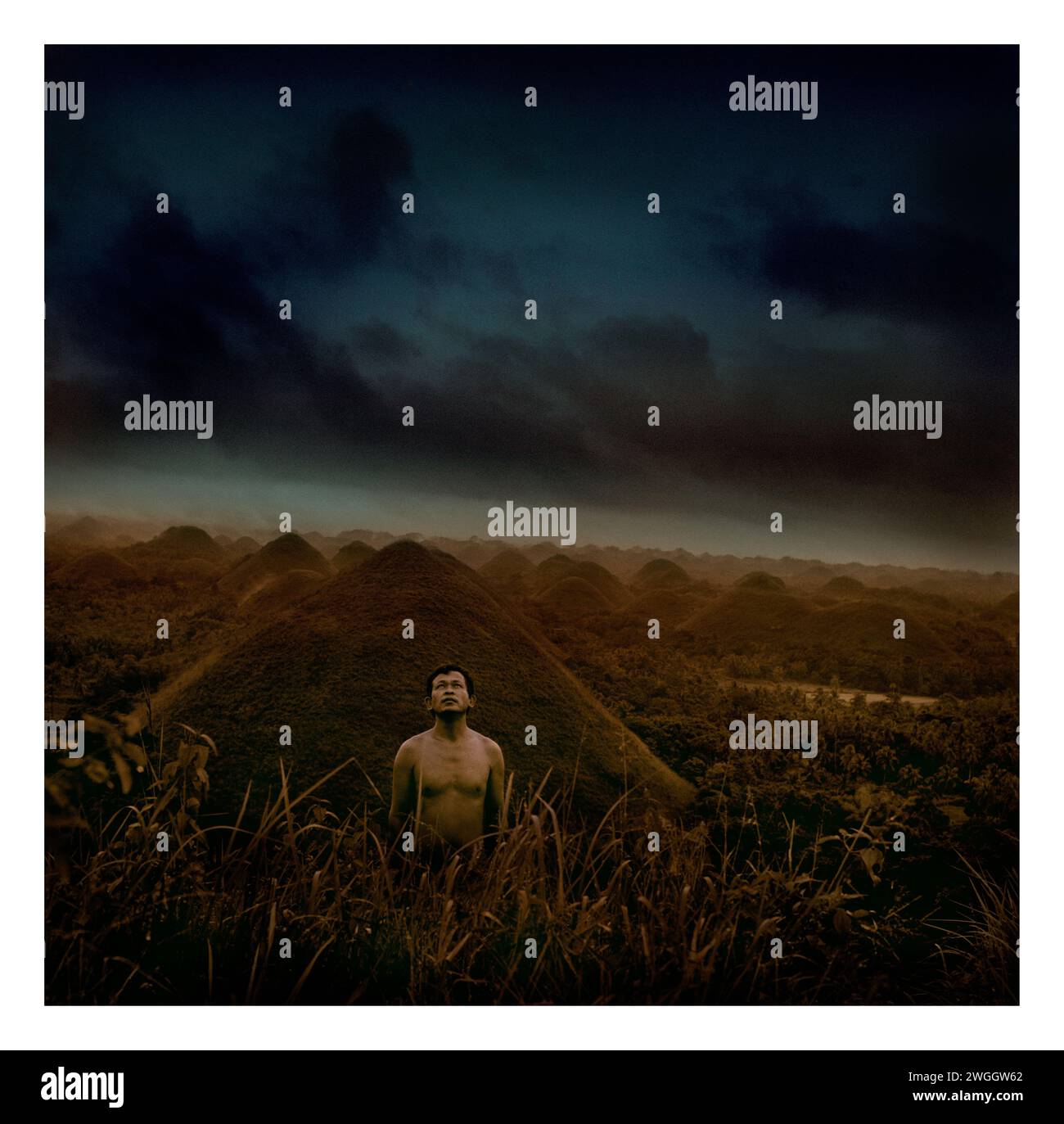 A local man stands in front of the Chocolate Hills on the island of ...