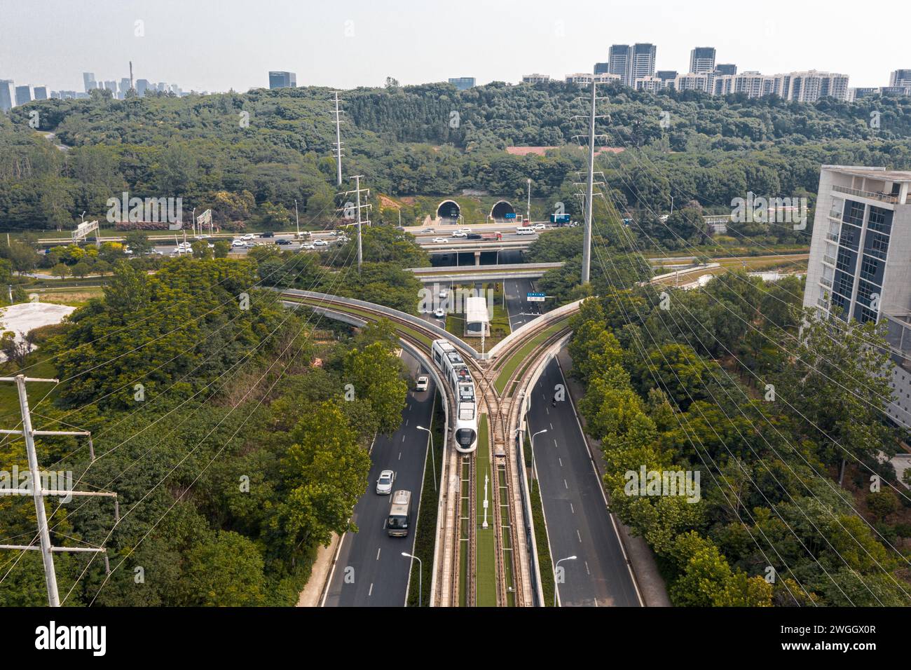 A transportation hub covered in green trees, with trains running on ...