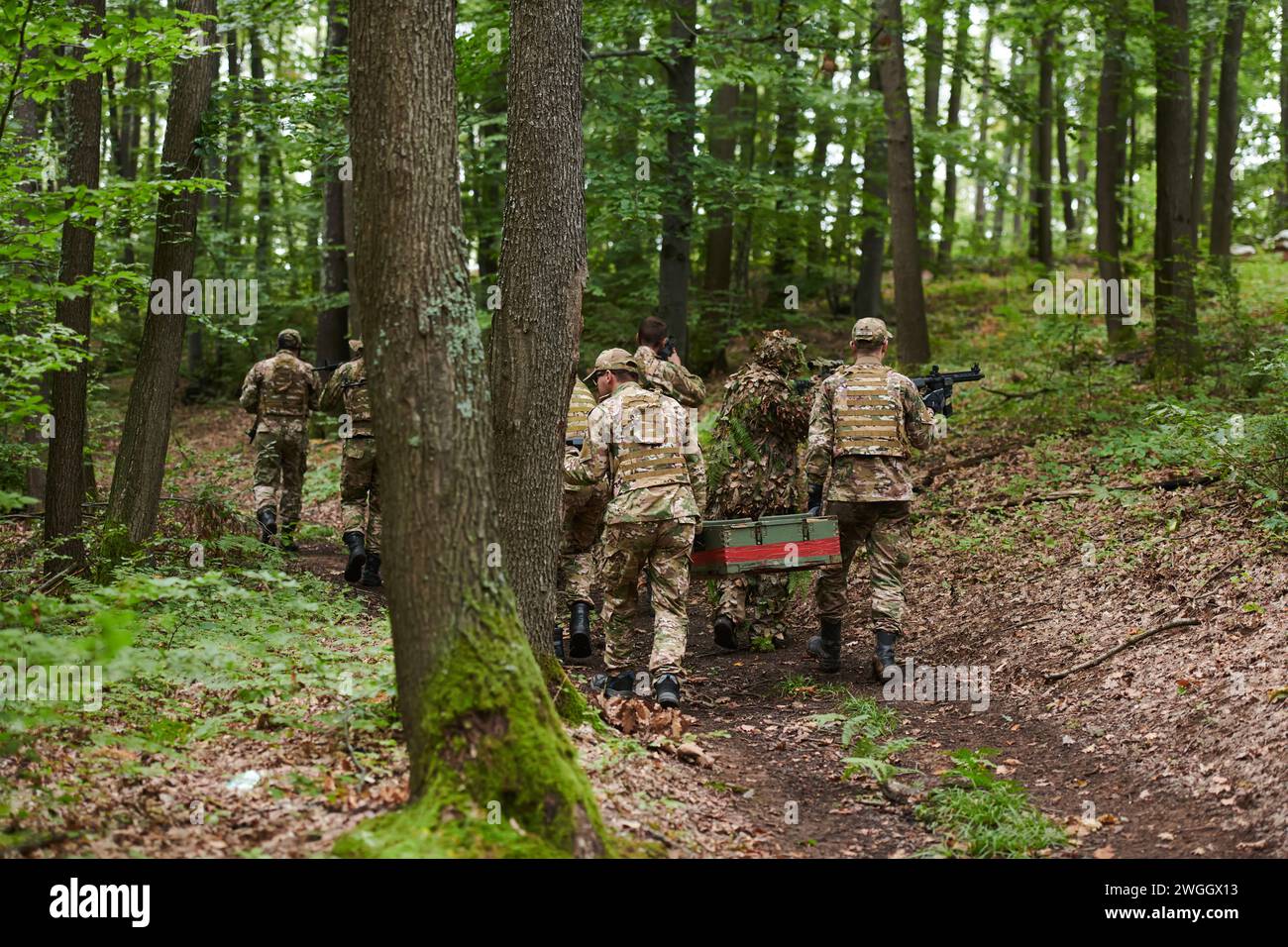 Elite military unit, cloaked in camouflage, transports a crate of ...