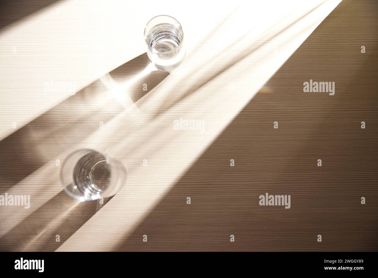 A water cup and shadow on a table in the sunlight Stock Photo - Alamy