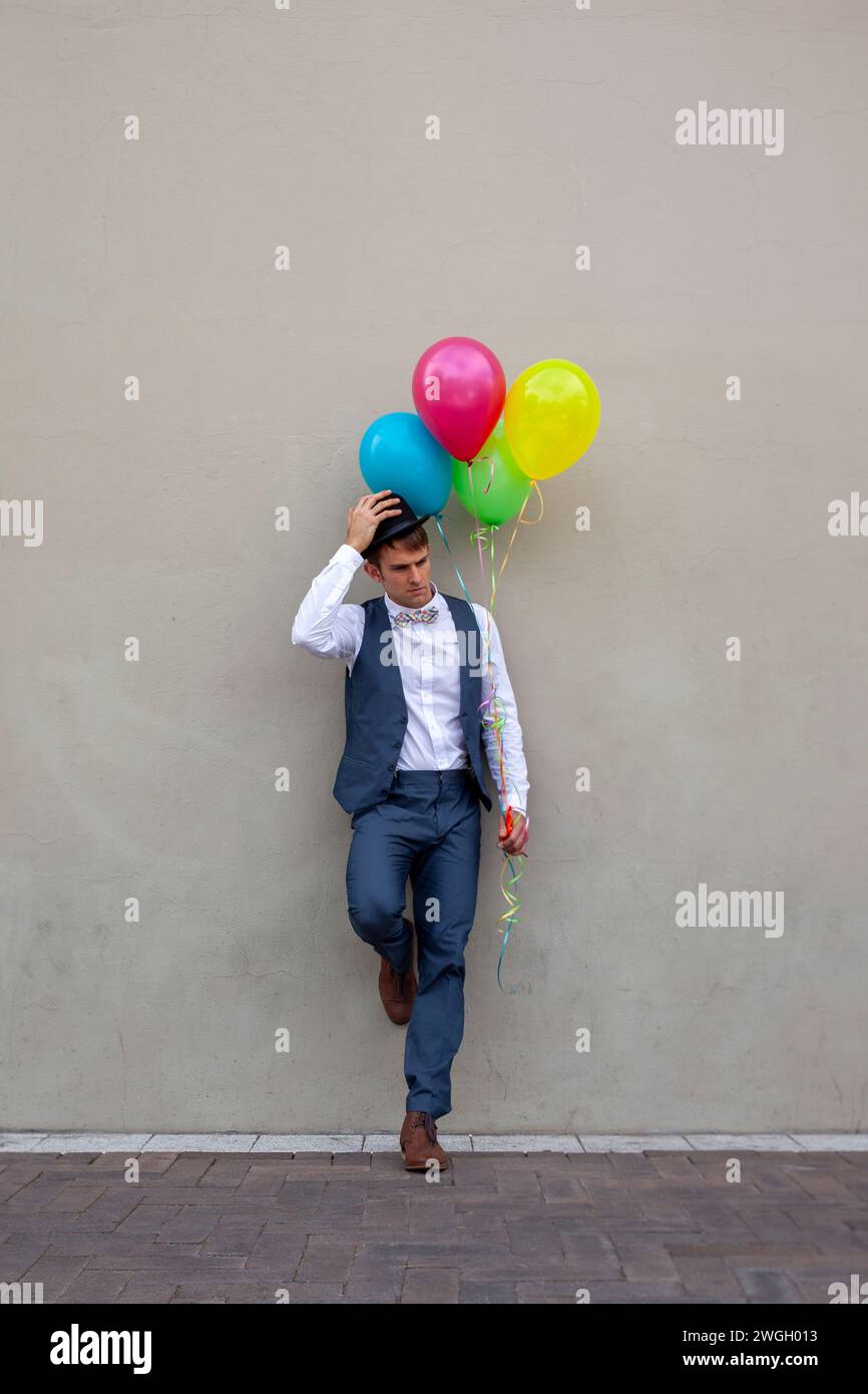 Man with colored balloons on sidewalk vertical Stock Photo - Alamy
