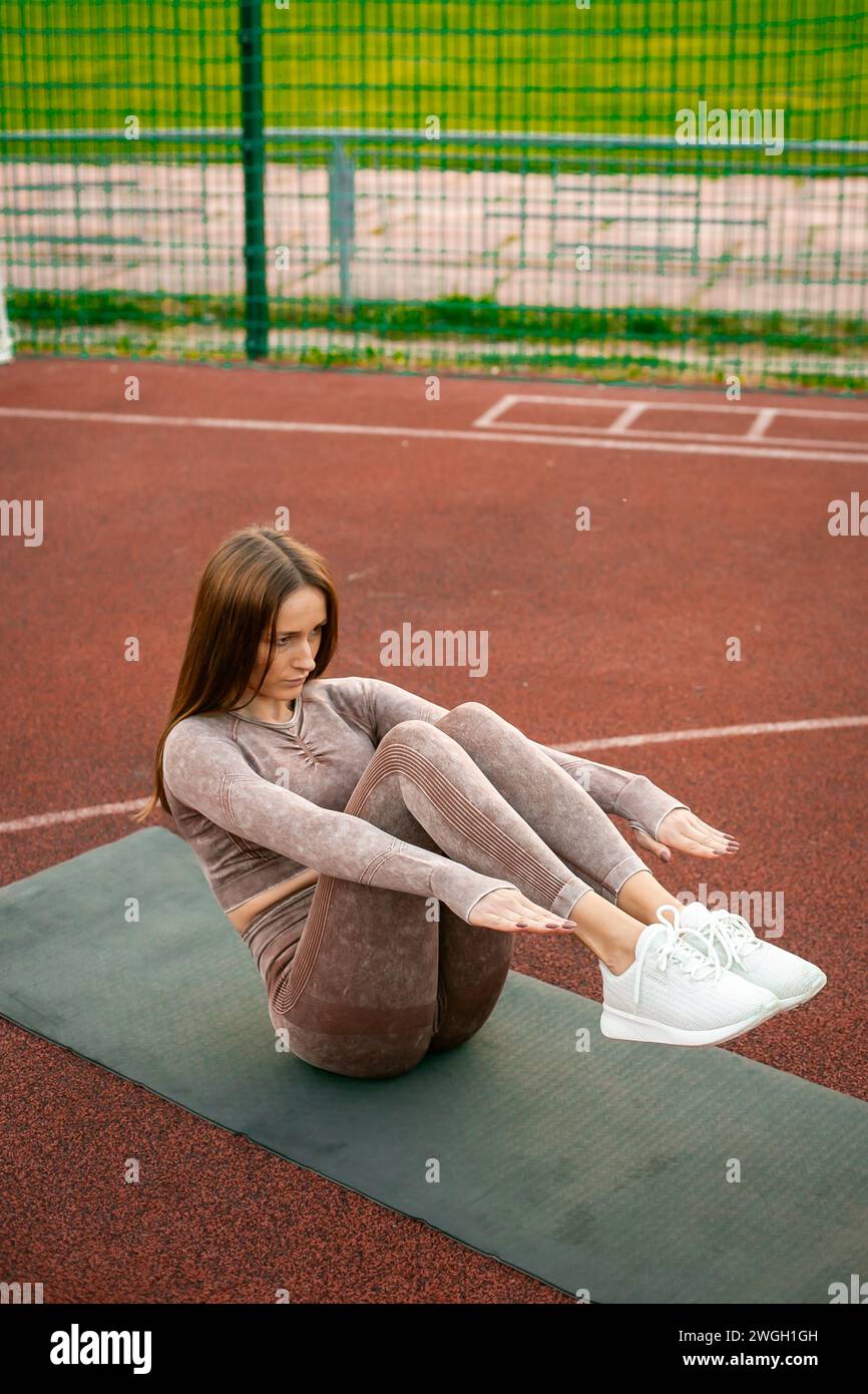 Vertical cropped photo of female athlete in brown sportswear doing ...