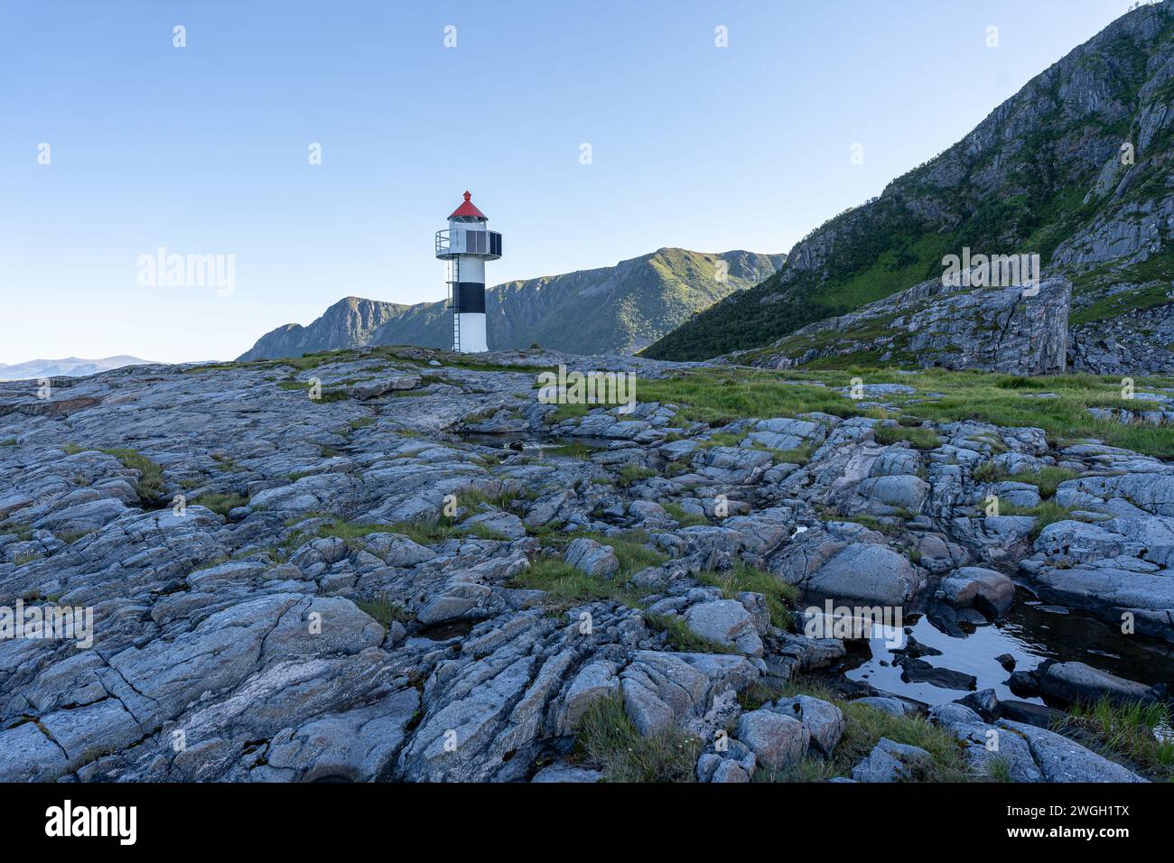 A picturesque black and white lighthouse stands on a hill, surrounded ...