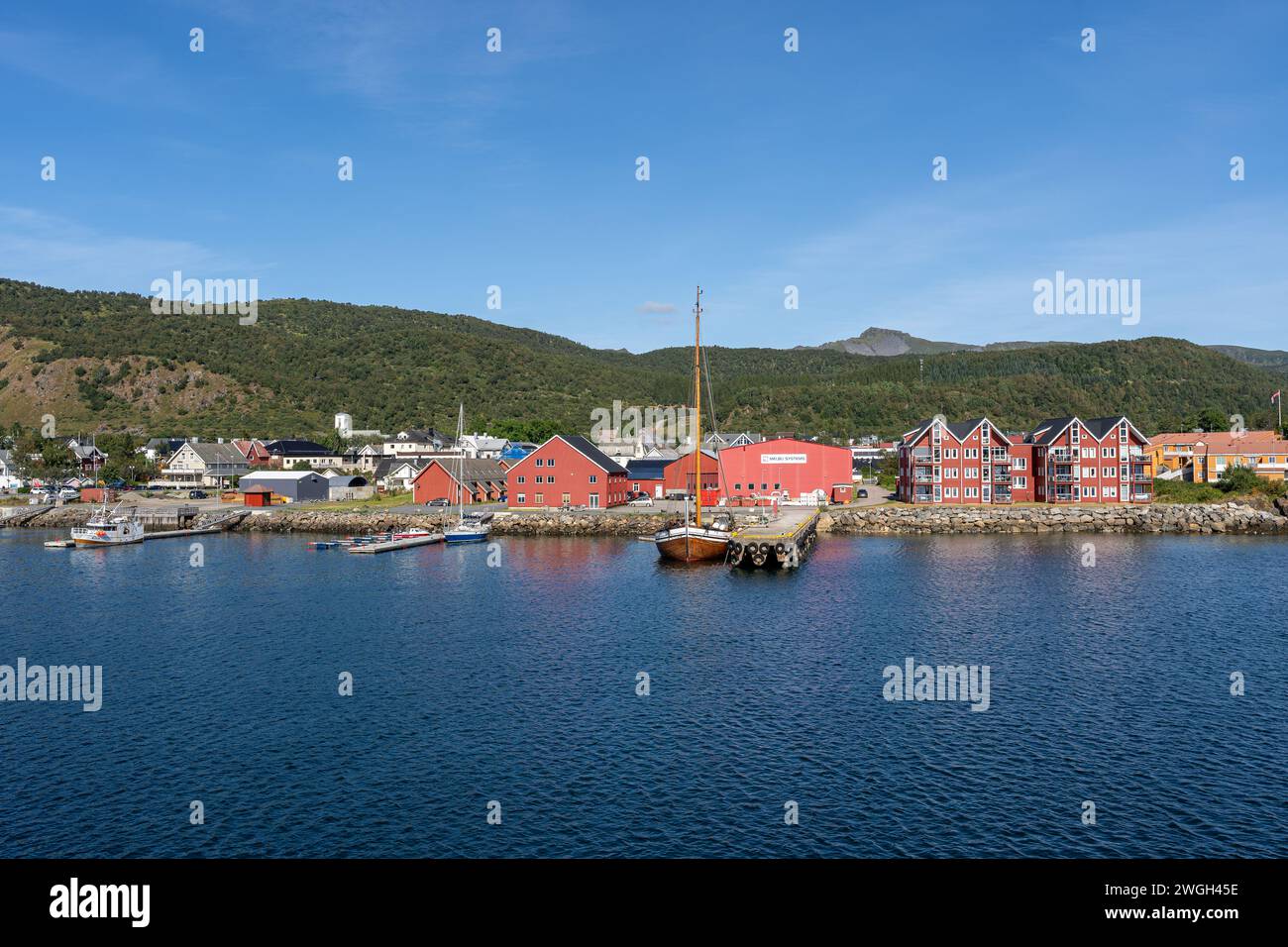 A picturesque harbor scene featuring boats, majestic mountains, and a ...