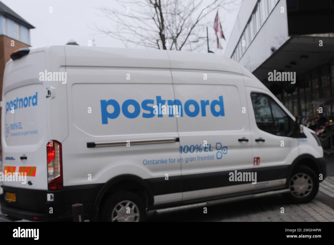 Copenhagen, Denmark /05 February/.Postnord parcels and packets delivery van and postman from ...
