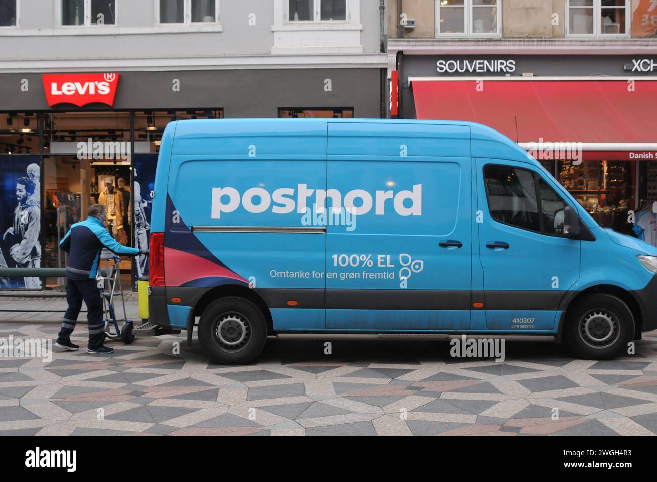 Copenhagen, Denmark /05 February/.Postnord parcels and packets delivery van and postman from ...