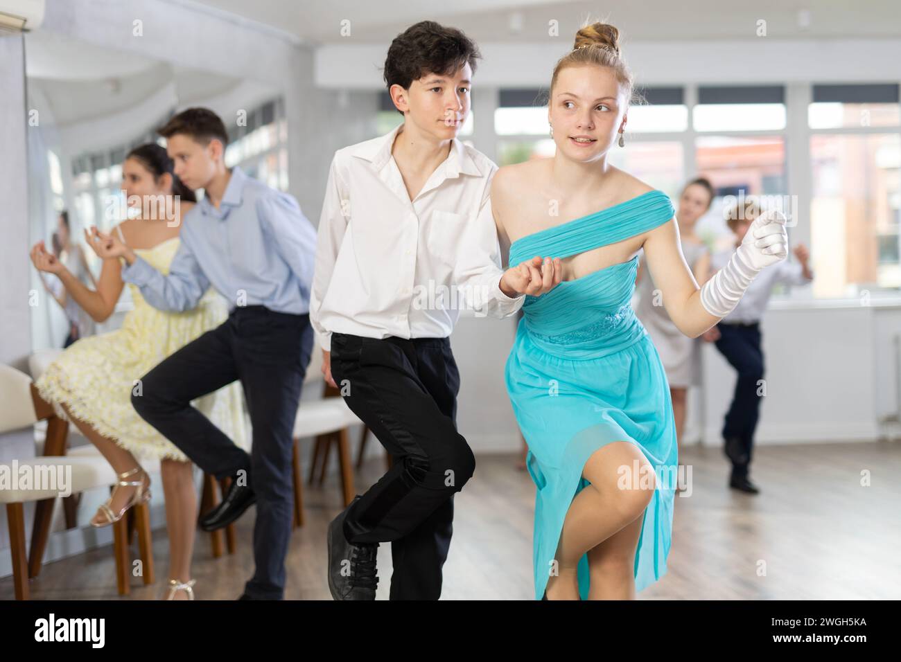 Teen girl in elegant evening dress dances incendiary twist with boy ...