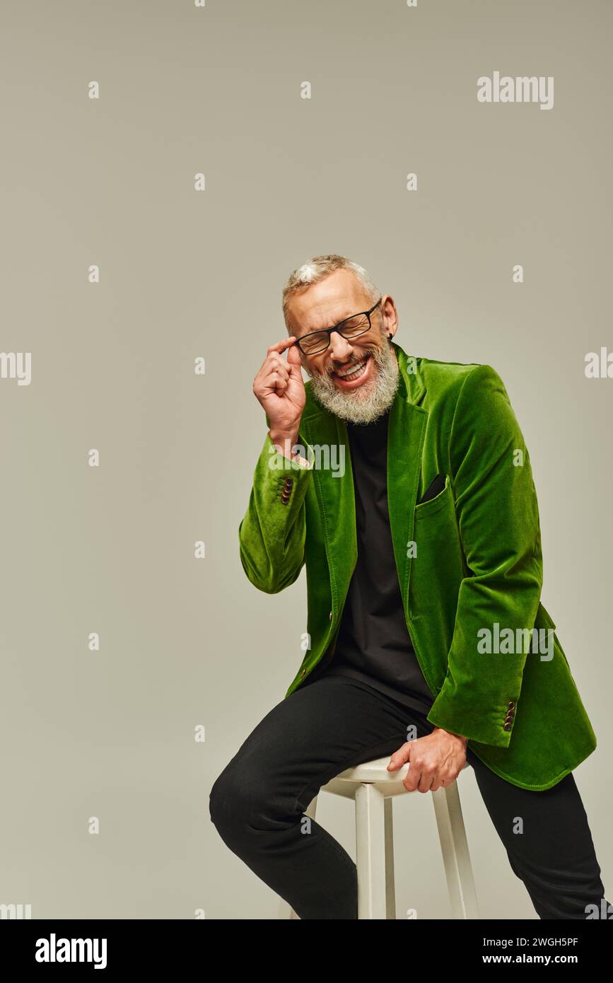 good looking funky man in green blazer sitting on tall chair and ...