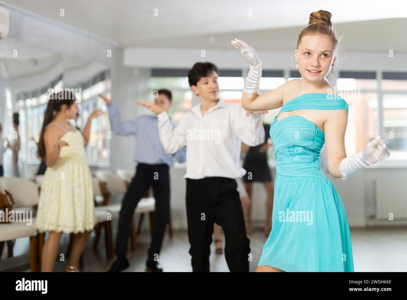 Teen girl in elegant evening dress dances incendiary twist with boy ...