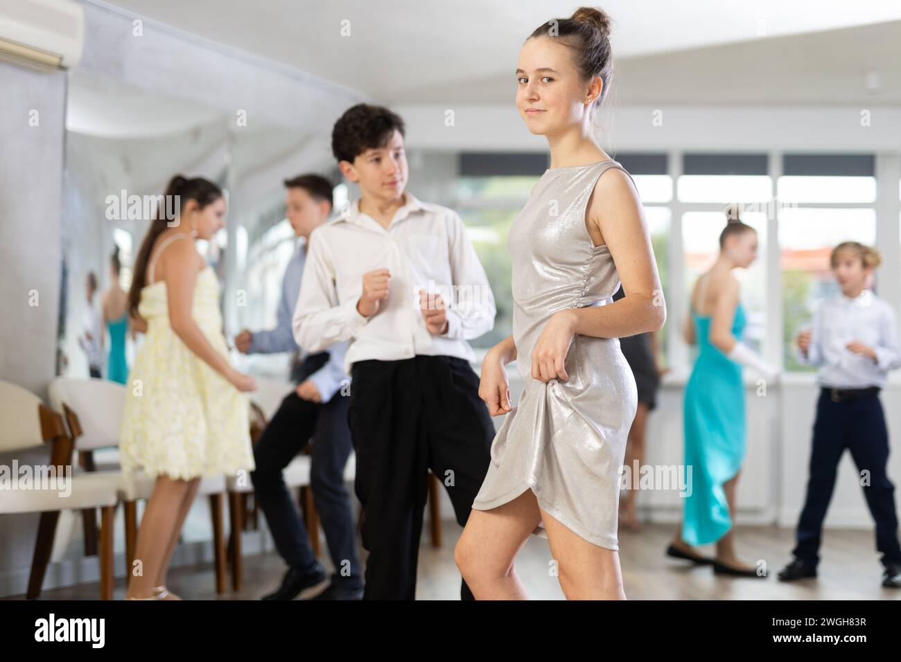 Teen girl in elegant evening dress dances incendiary twist with boy ...