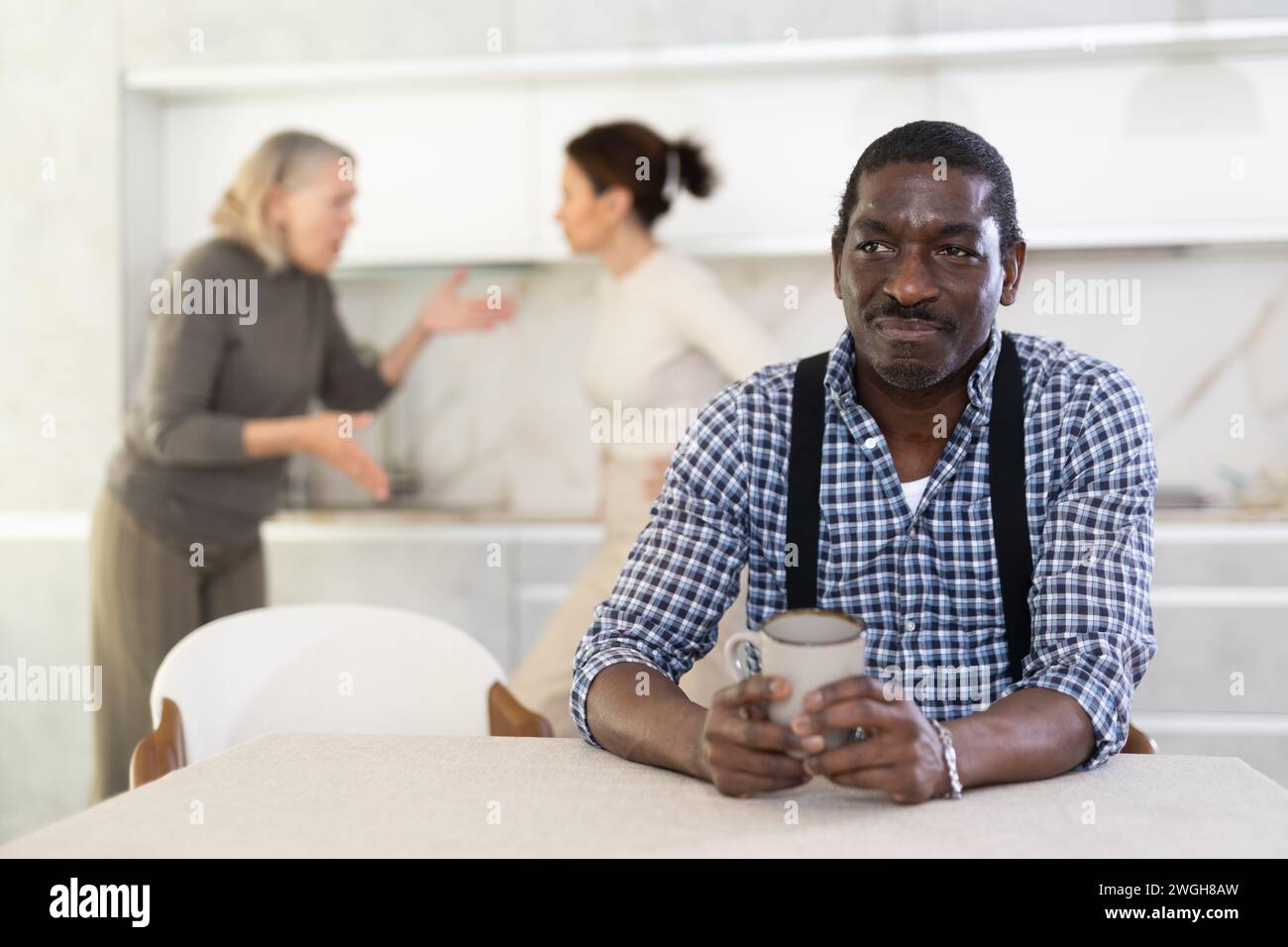 Adult sad man sitting at table during family quarrel Stock Photo - Alamy