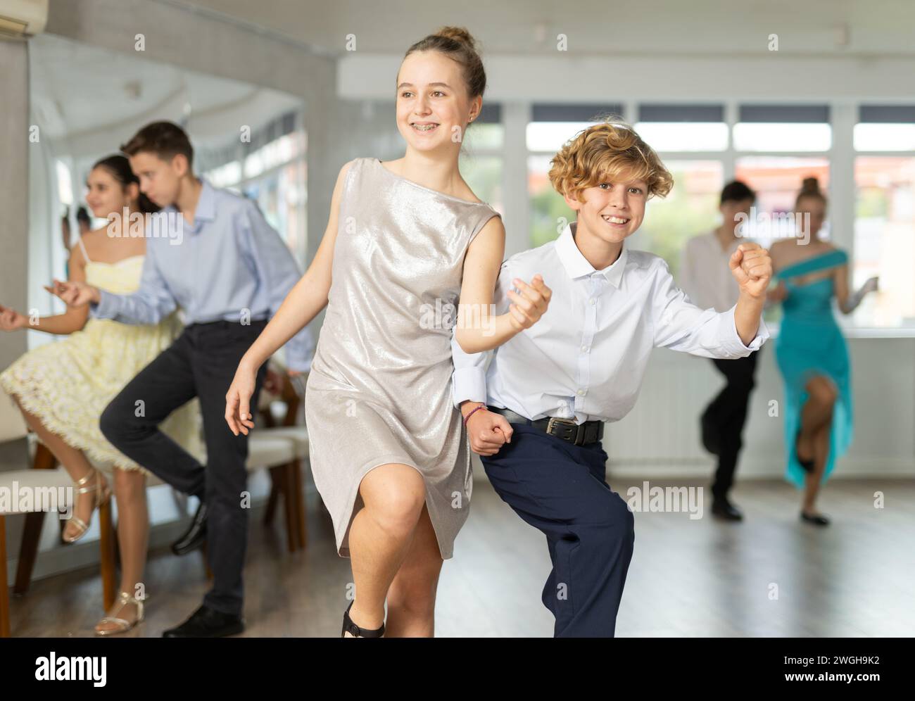 Teen girl in elegant evening dress dances incendiary twist with boy ...