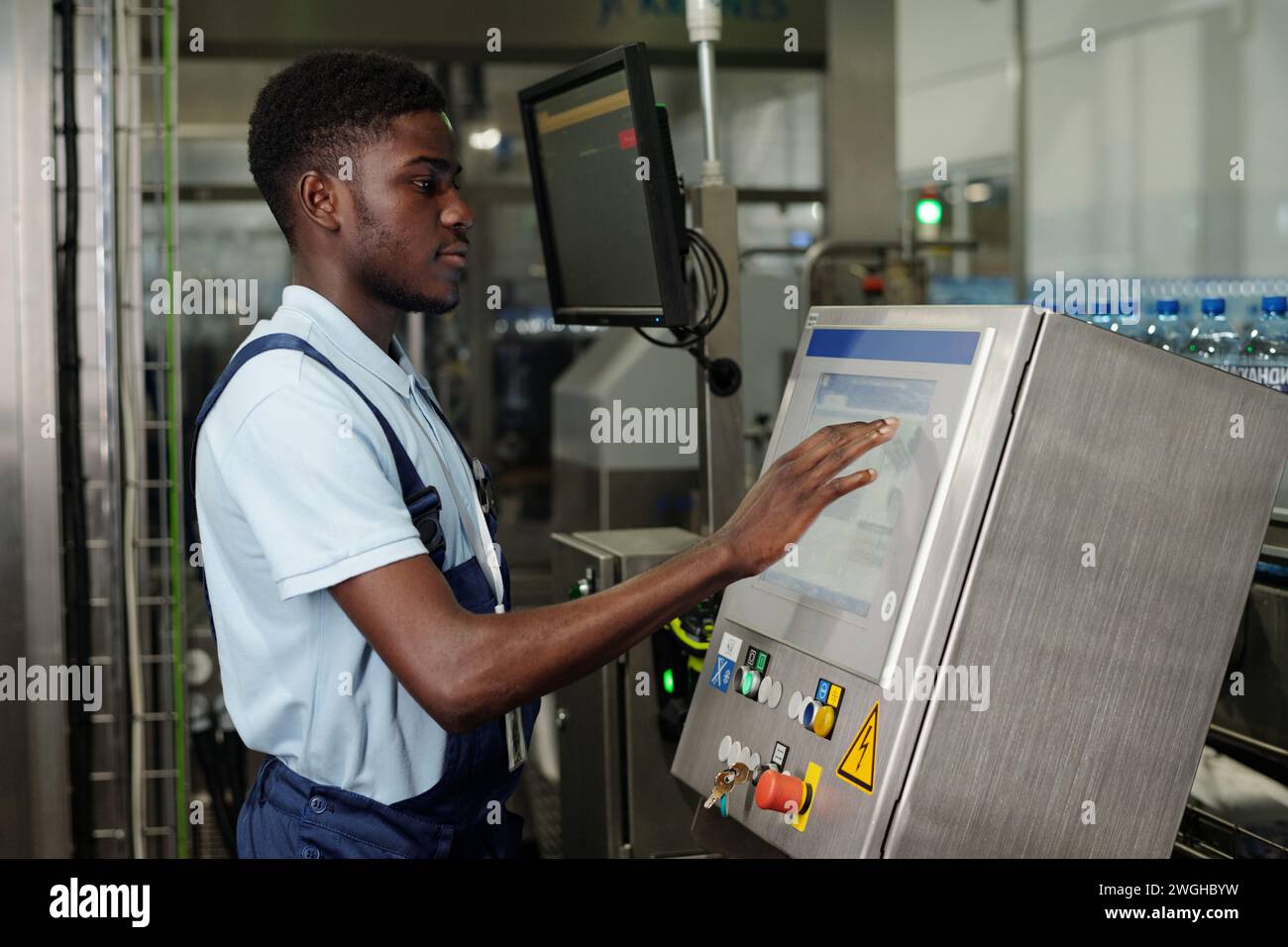 Young African American worker standing in front of display of factory ...