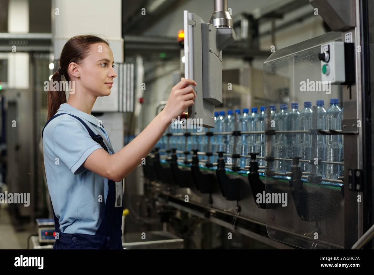 Young quality control inspector looking at screen while standing in ...