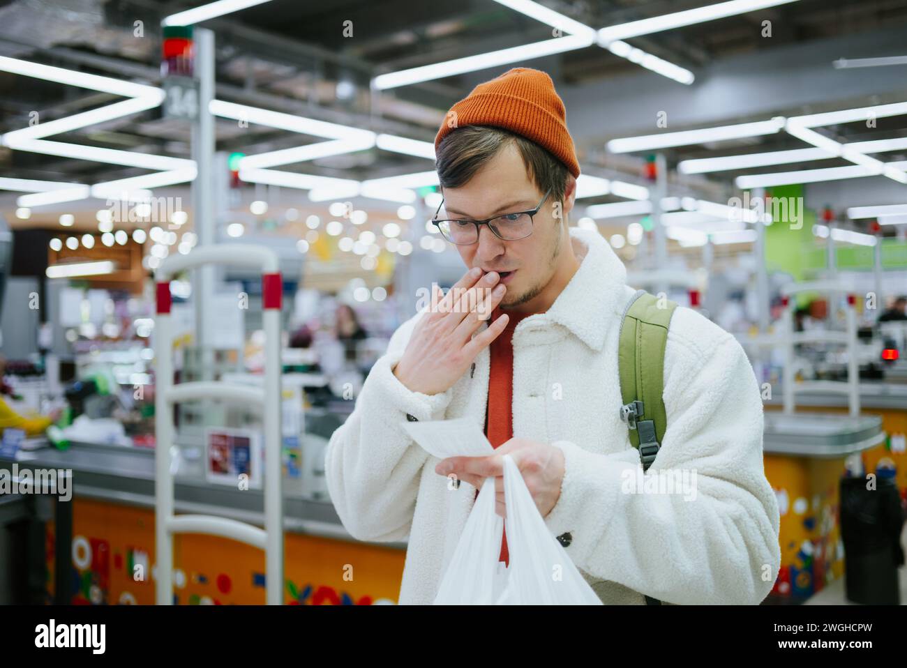A man at the supermarket checkout is looking through a paper receipt ...