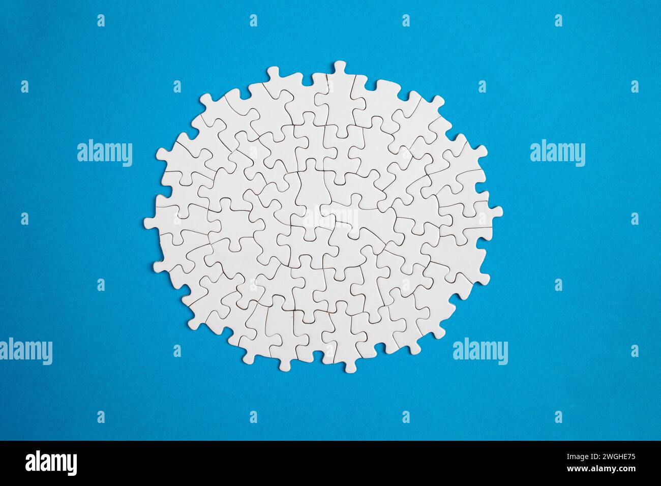 Plain white jigsaw puzzle on blue color background, oval shaped frame ...