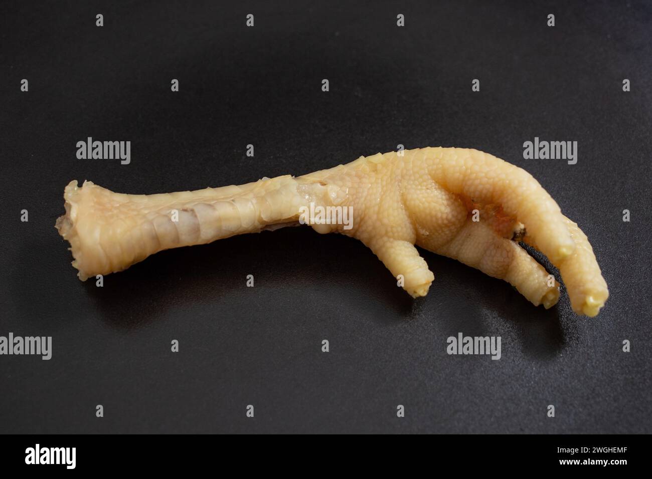 Boiled chicken foot on a black ceramic plate texture, background for ...