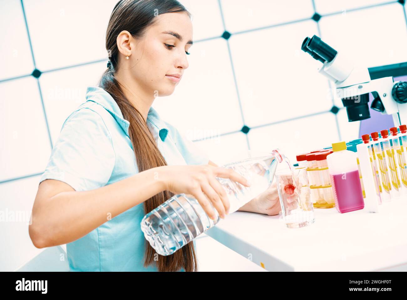young woman in the laboratory measures the acidity of drinking water ...