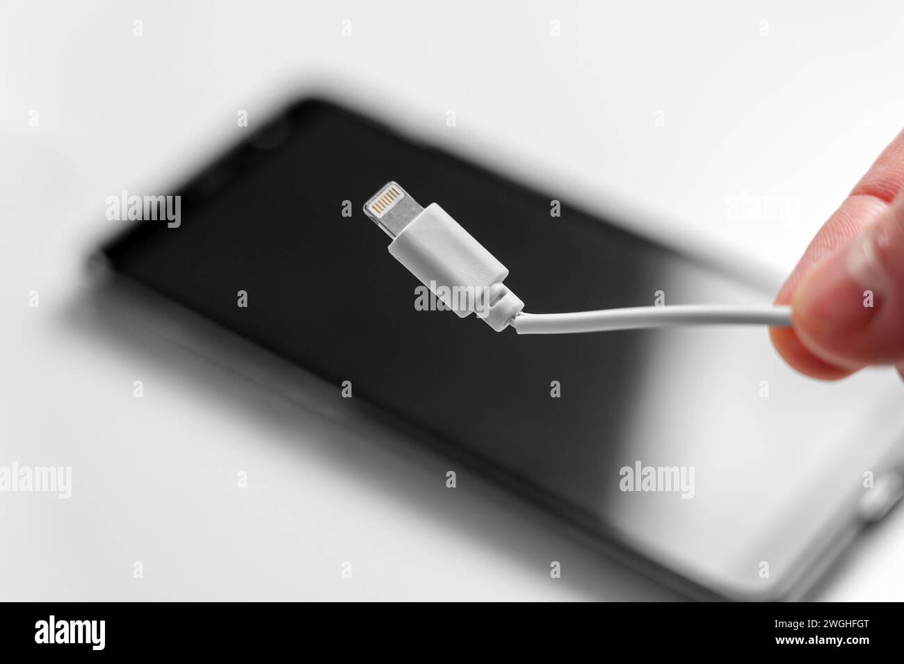 White broken cable with smartphone charging plug in hand close up ...