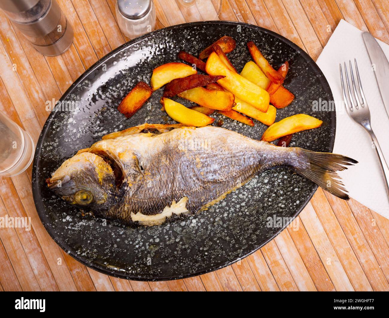 Baked dorada fish with vegetable garnish of fried potatoes Stock Photo ...