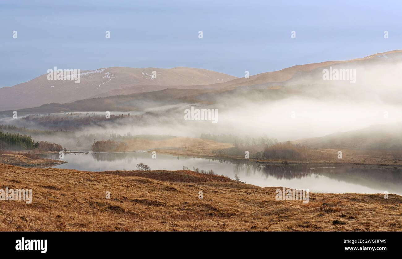 Morning mist rising over a Loch and hills in winter on the West Coast ...