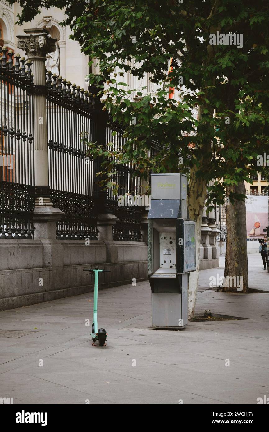 old telephone booth in contrast with electric scooter in Madrid in ...