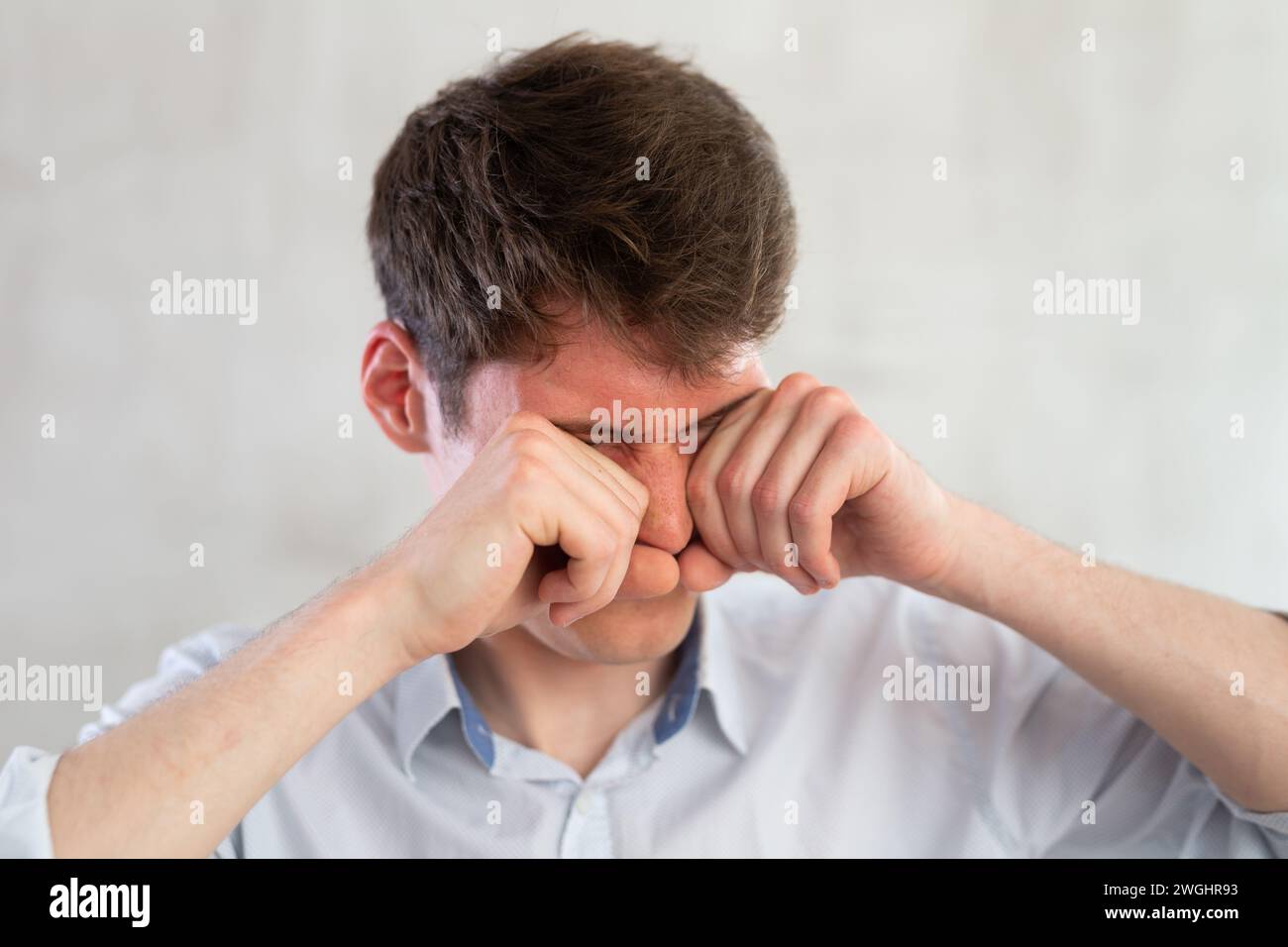 Man scretching itchy eyes on gray background Stock Photo - Alamy