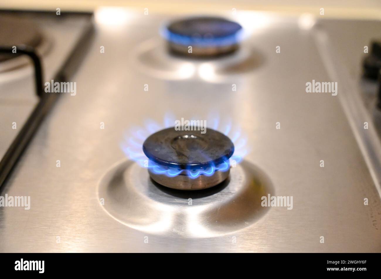 Gas cooker in kitchen. Blue flames on gas stove burner in home. Close ...