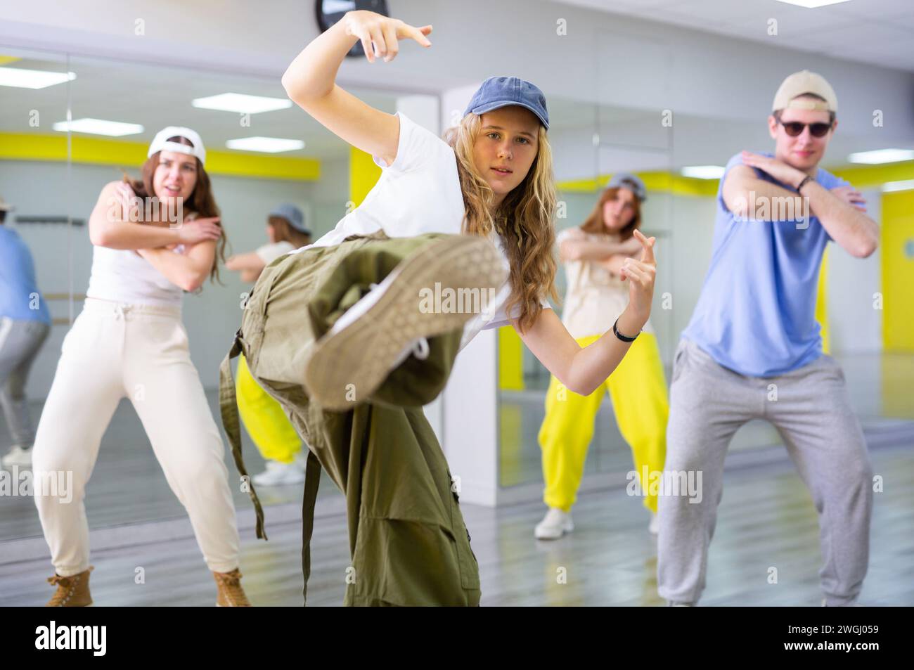 Ordinary teen girls and boy performing kick step movement during ...