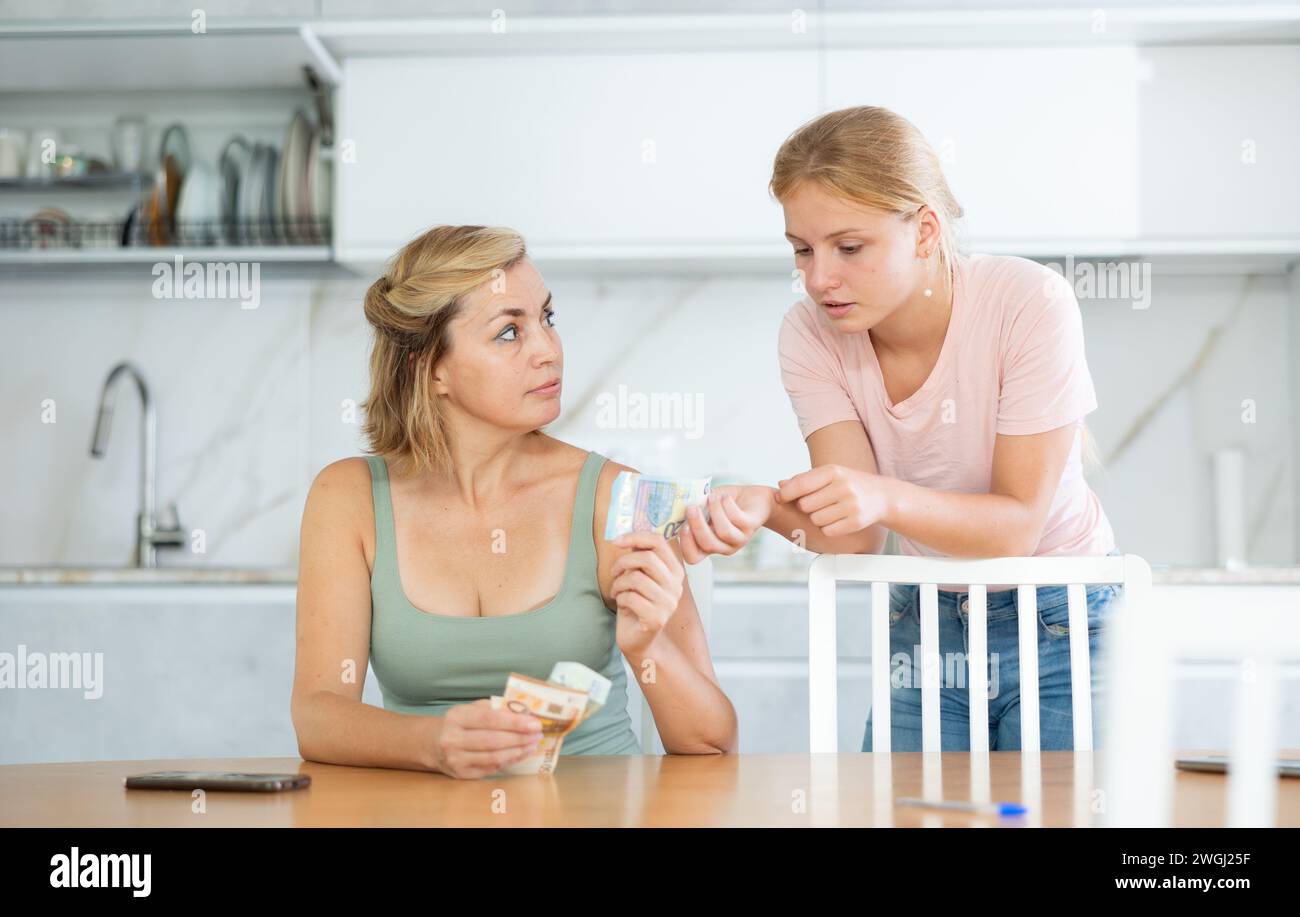 Teenage girl asking for pocket money from mother counting received ...