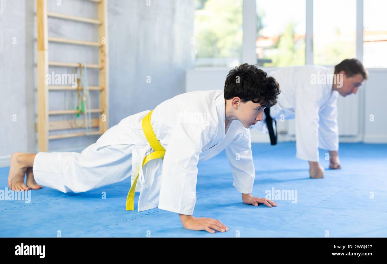 Boy and coach doing muscle stretching before boxing or judo class ...
