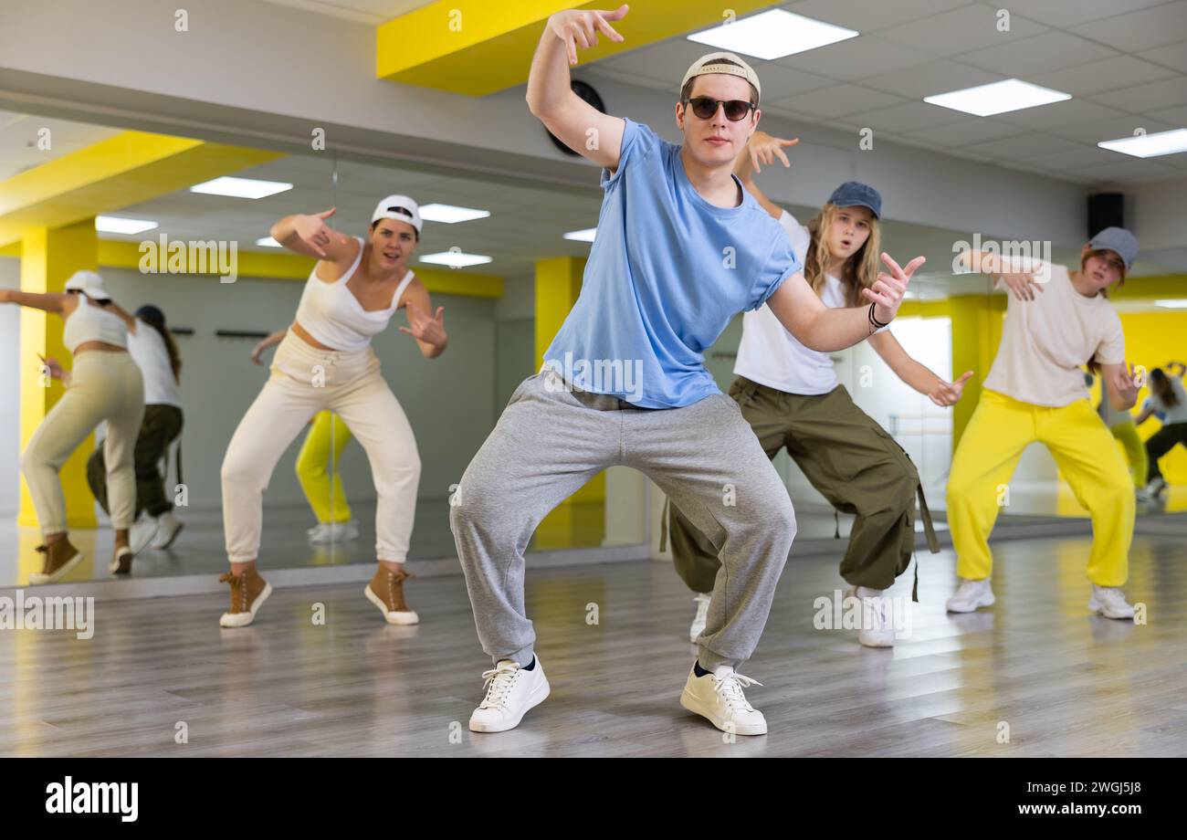 Cool talented teens in casual wear exercising modern dance moves in ...