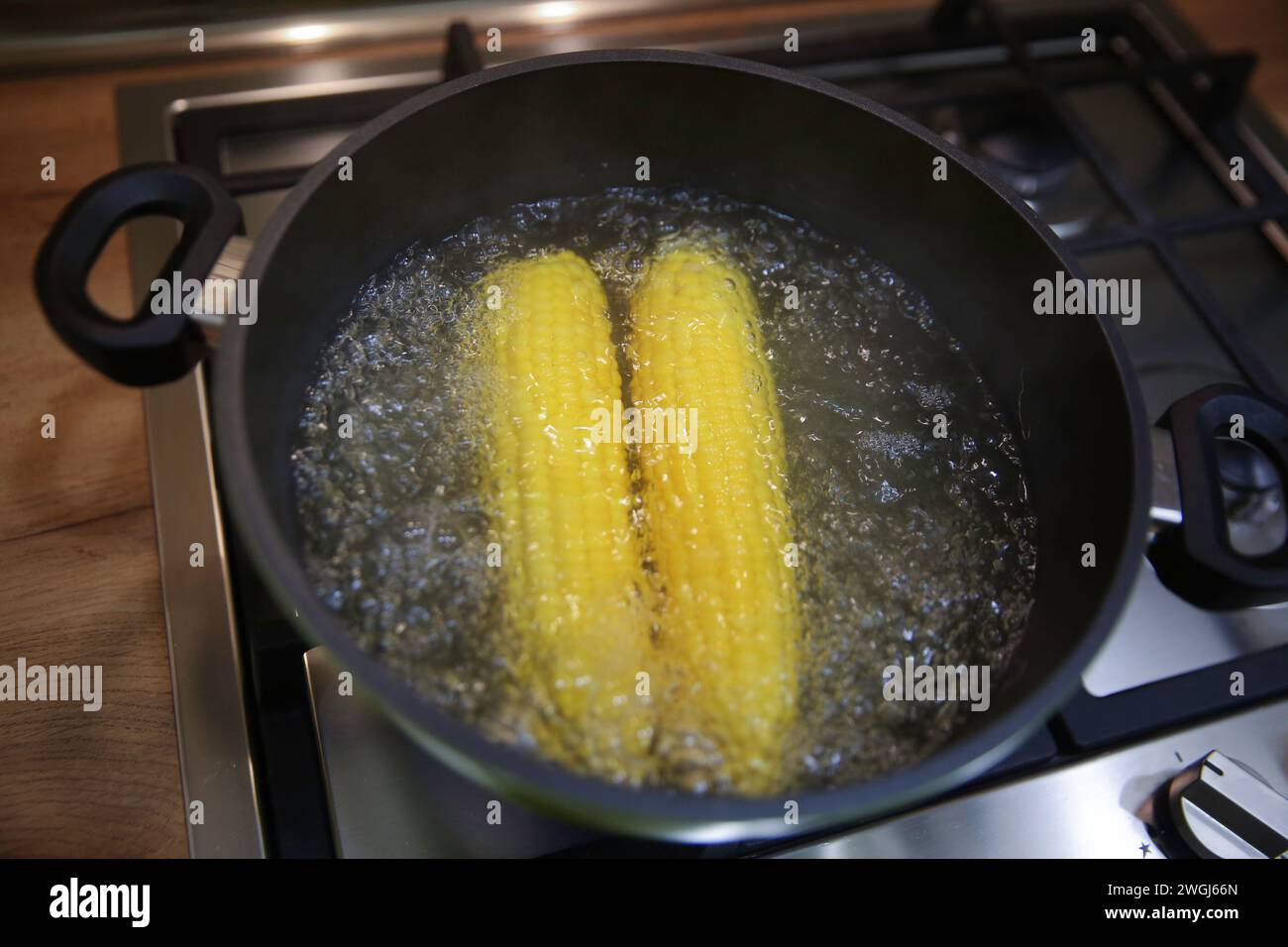 The corn cooking in a sizzling stovetop frying pan Stock Photo - Alamy