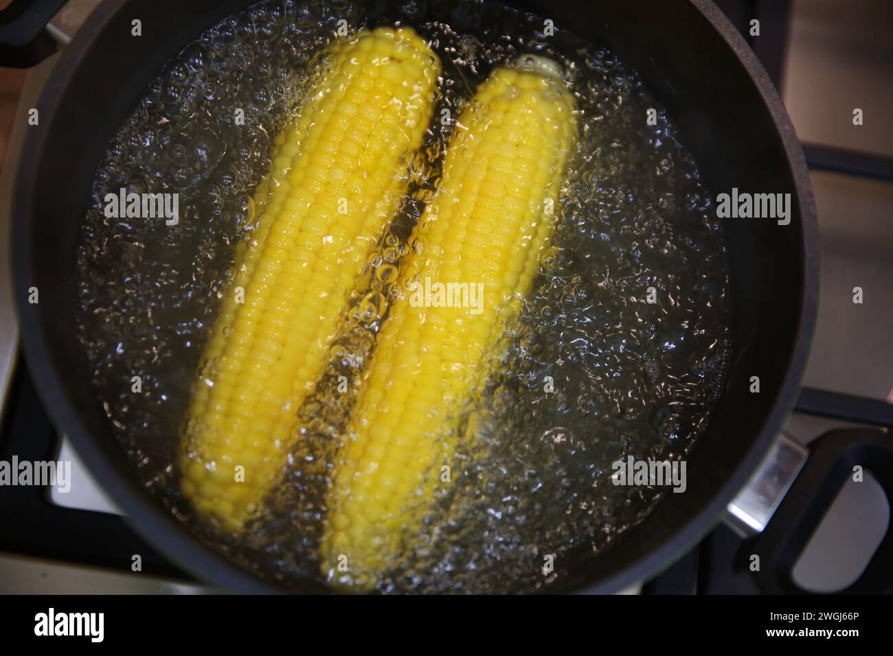 The corn cooking in a sizzling stovetop frying pan Stock Photo - Alamy