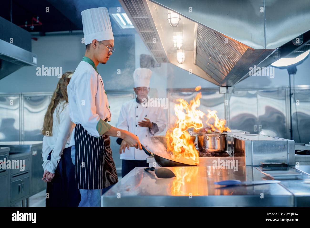 Senior male chef teaches young teenage boys cooking in school kitchen ...