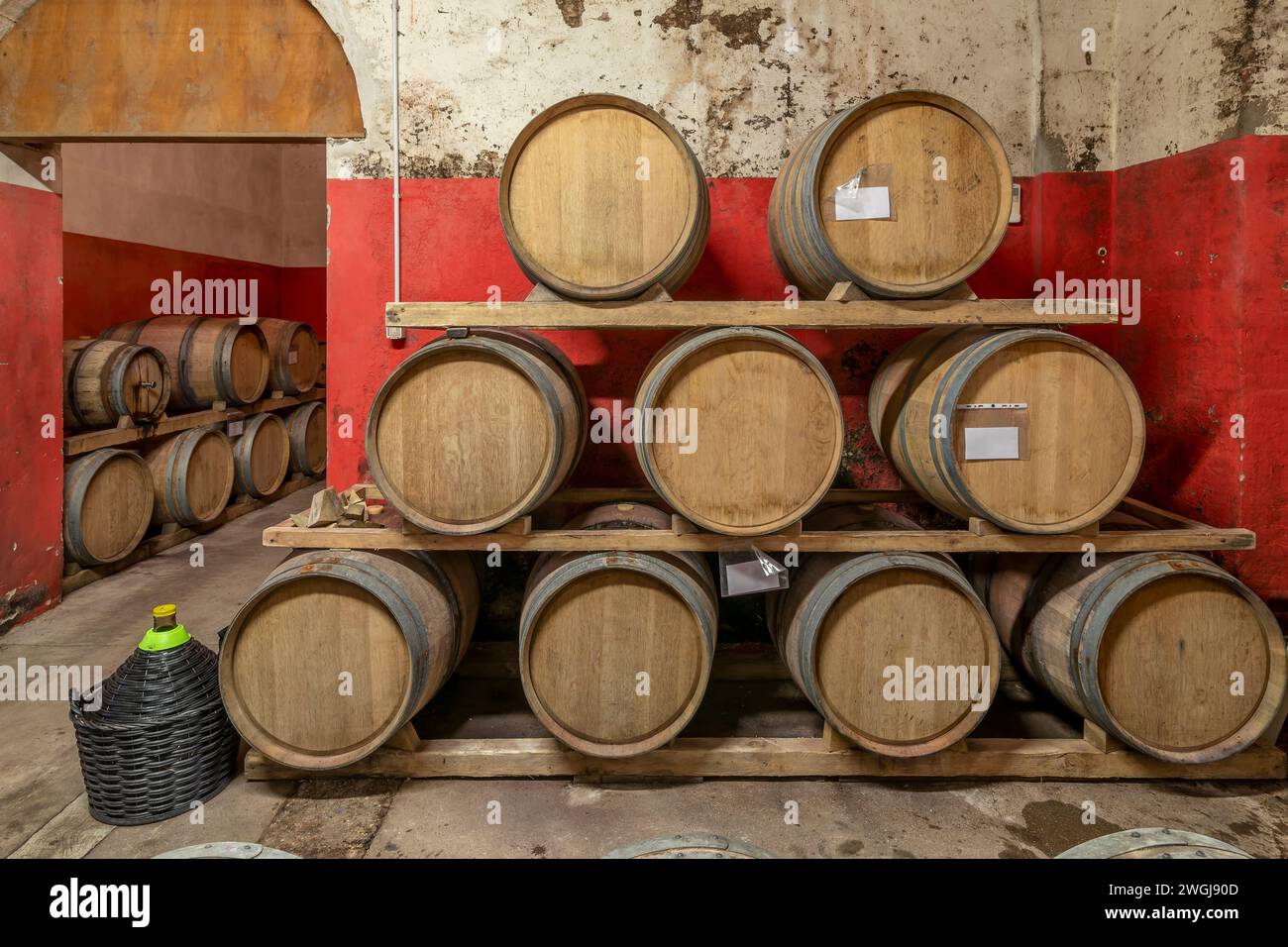 Wooden barriques for wine aging are arranged on three levels in a ...