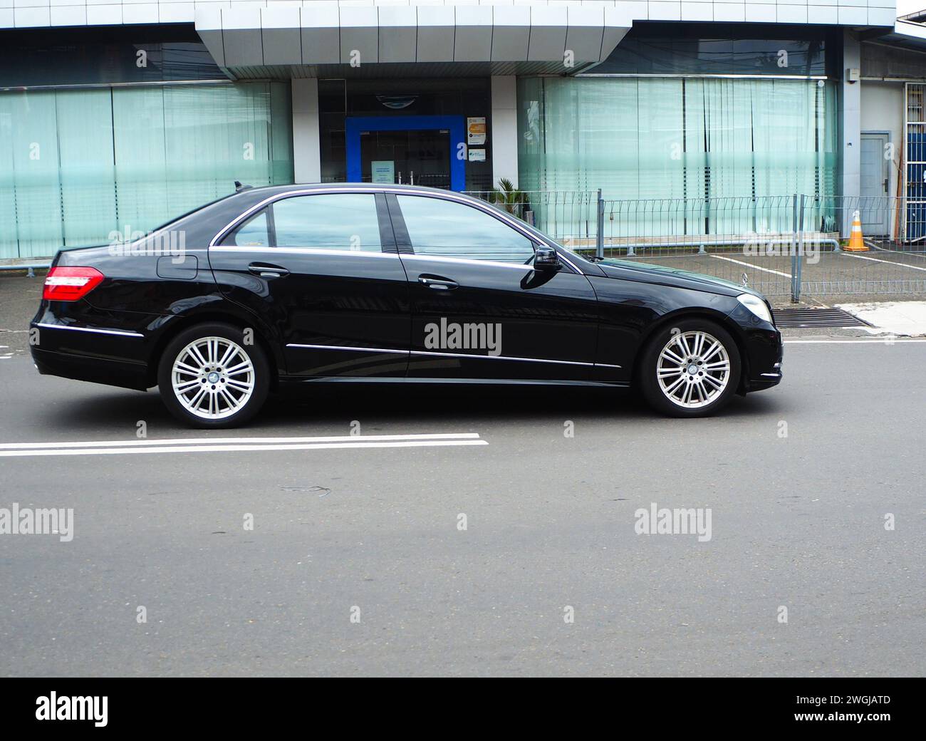 Luxury sedan car, black Mercedes Benz CLS, driving in commercial area ...