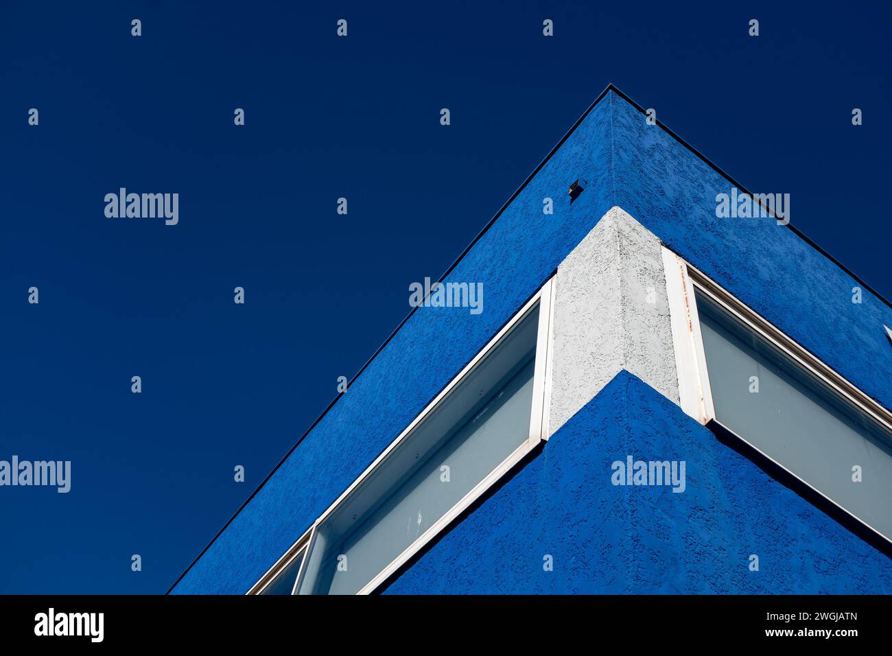 Blue building with white stripe against blue sky Stock Photo - Alamy