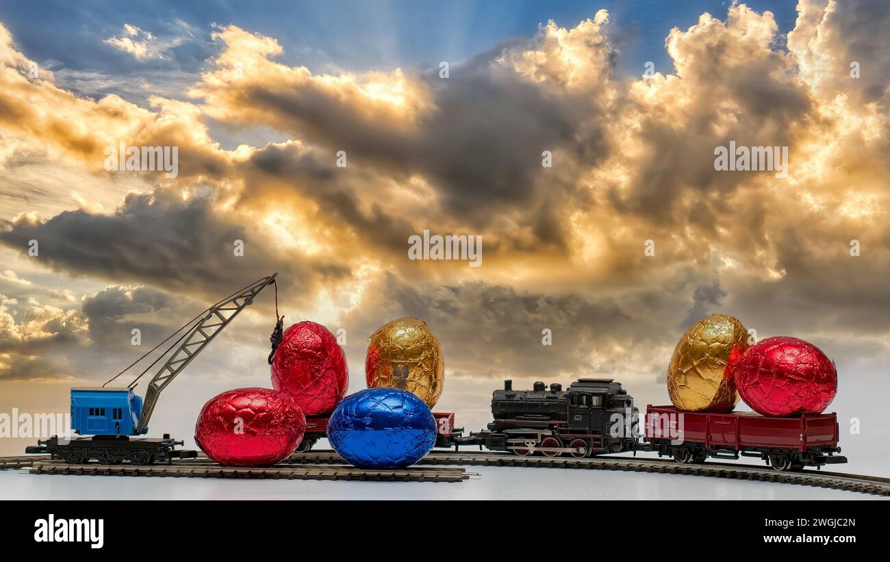 A toy train filled with easter candy eggs against a cloudy sky, the ...