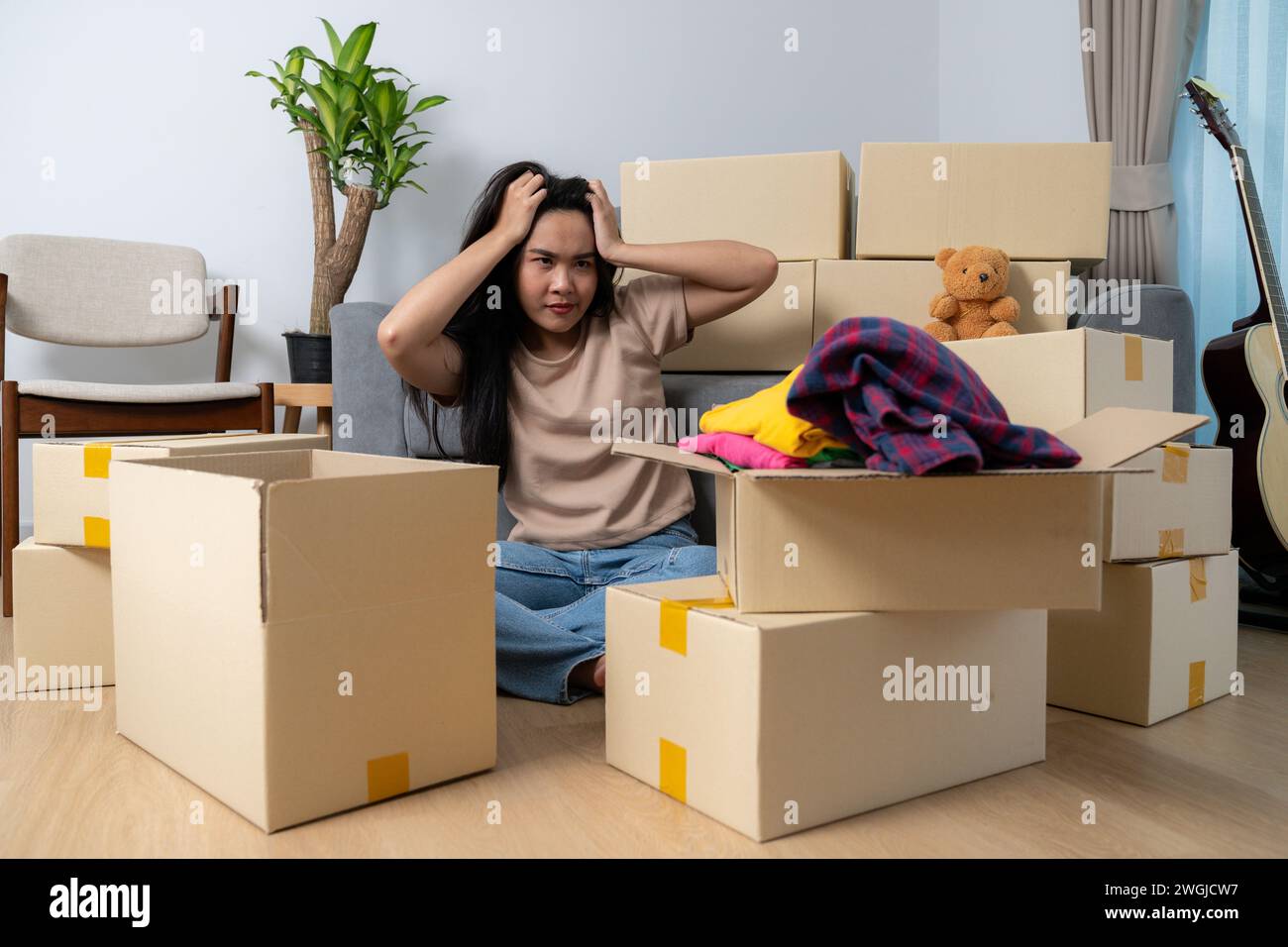 A tired young woman packing her belongings in boxes, preparing to move ...