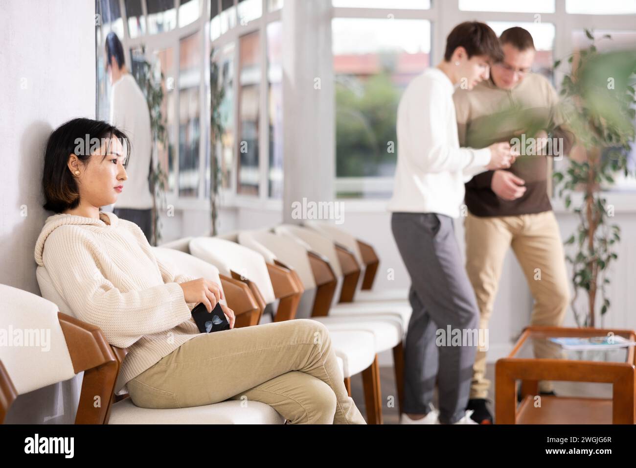 Young woman sitting in line at reception Stock Photo - Alamy