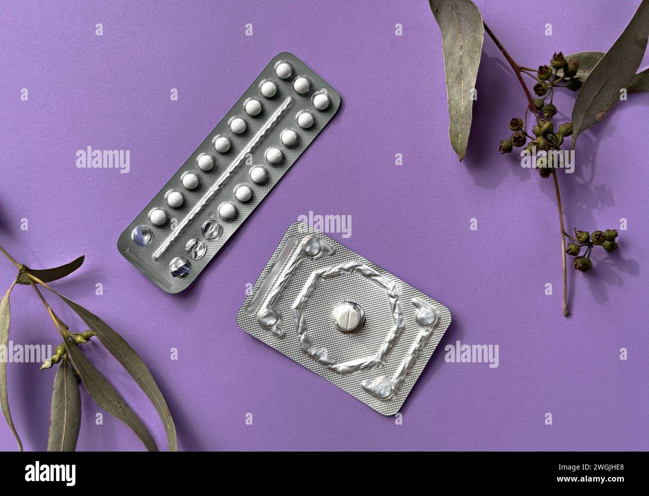 Two different packs of contraceptive pills on colored paper background ...