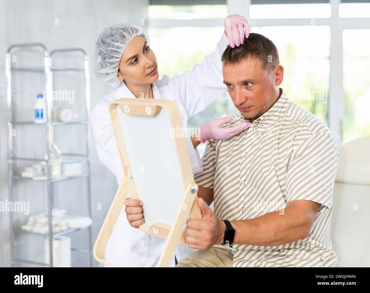Satisfied middle-aged man patient holding mirror sitting on clinical ...